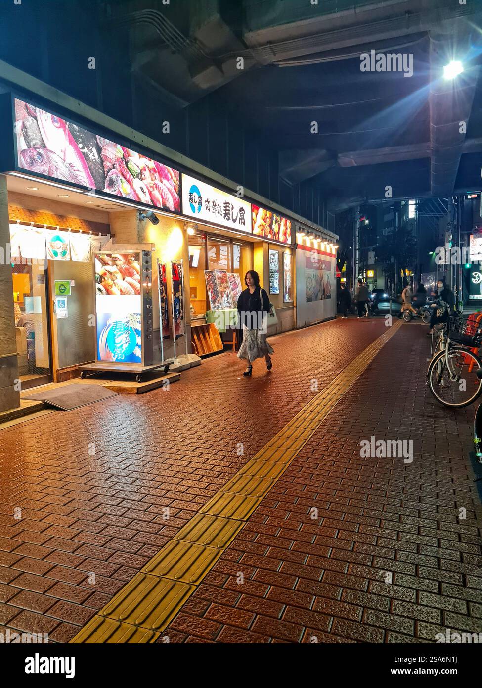 Row of restaurants at night in Tokyo, Japan under a train bridge in ...