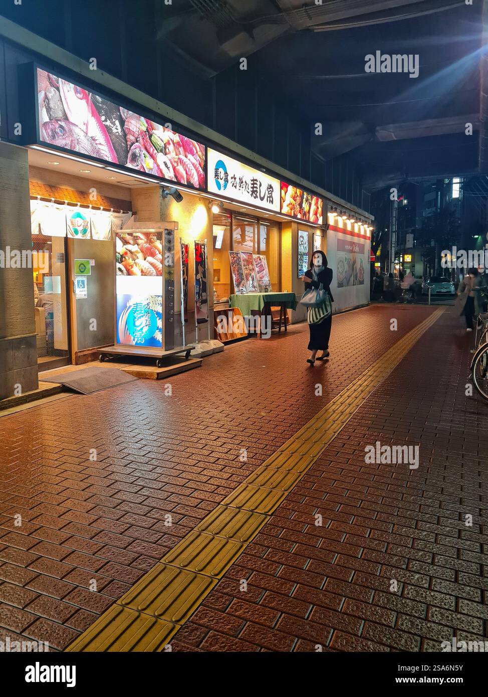 Row of restaurants at night in Tokyo, Japan under a train bridge in ...