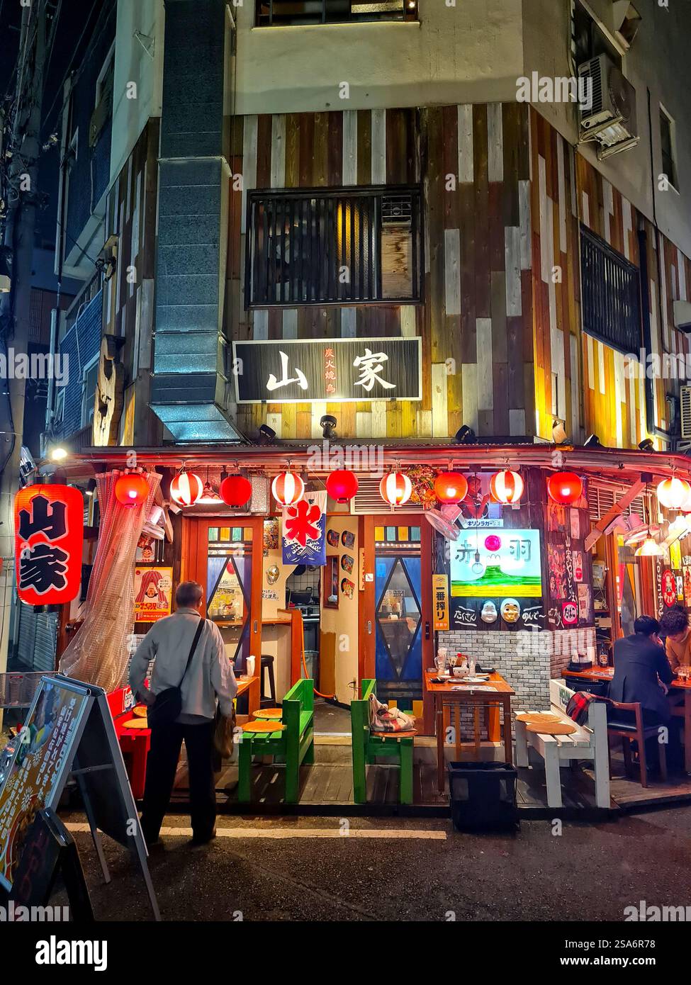 A restaurant at night with people and outdoor seating in the Akabane ...