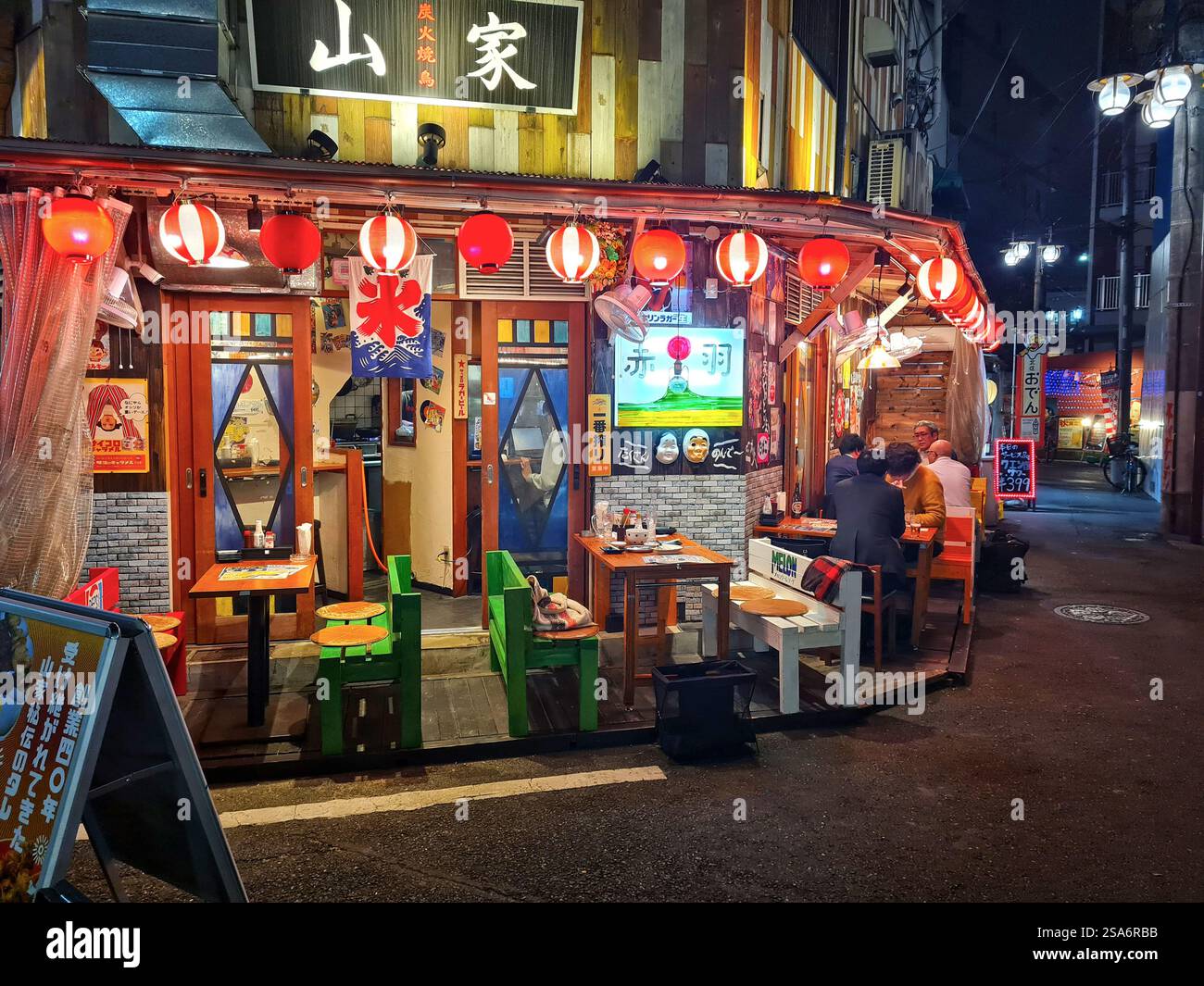 A restaurant at night with people and outdoor seating in the Akabane ...