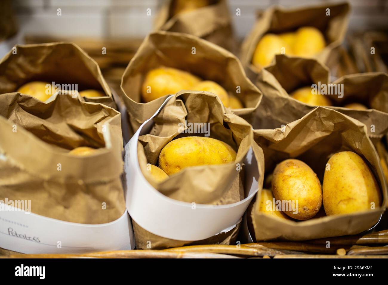 Yellow potatoes displayed in kraft paper bags at market, showing ...