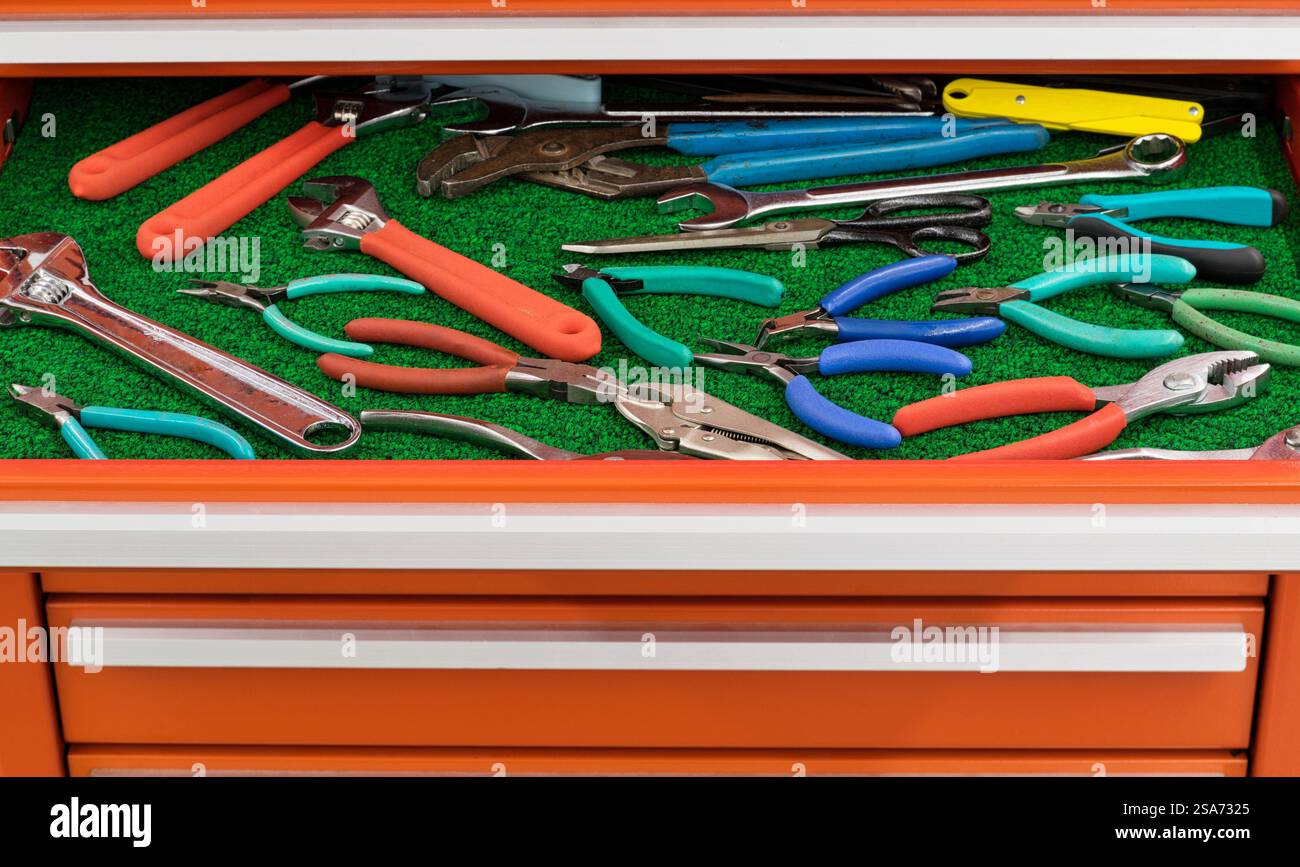 Assorted pliers wrench clamping tools displayed in open toolbox drawer ...