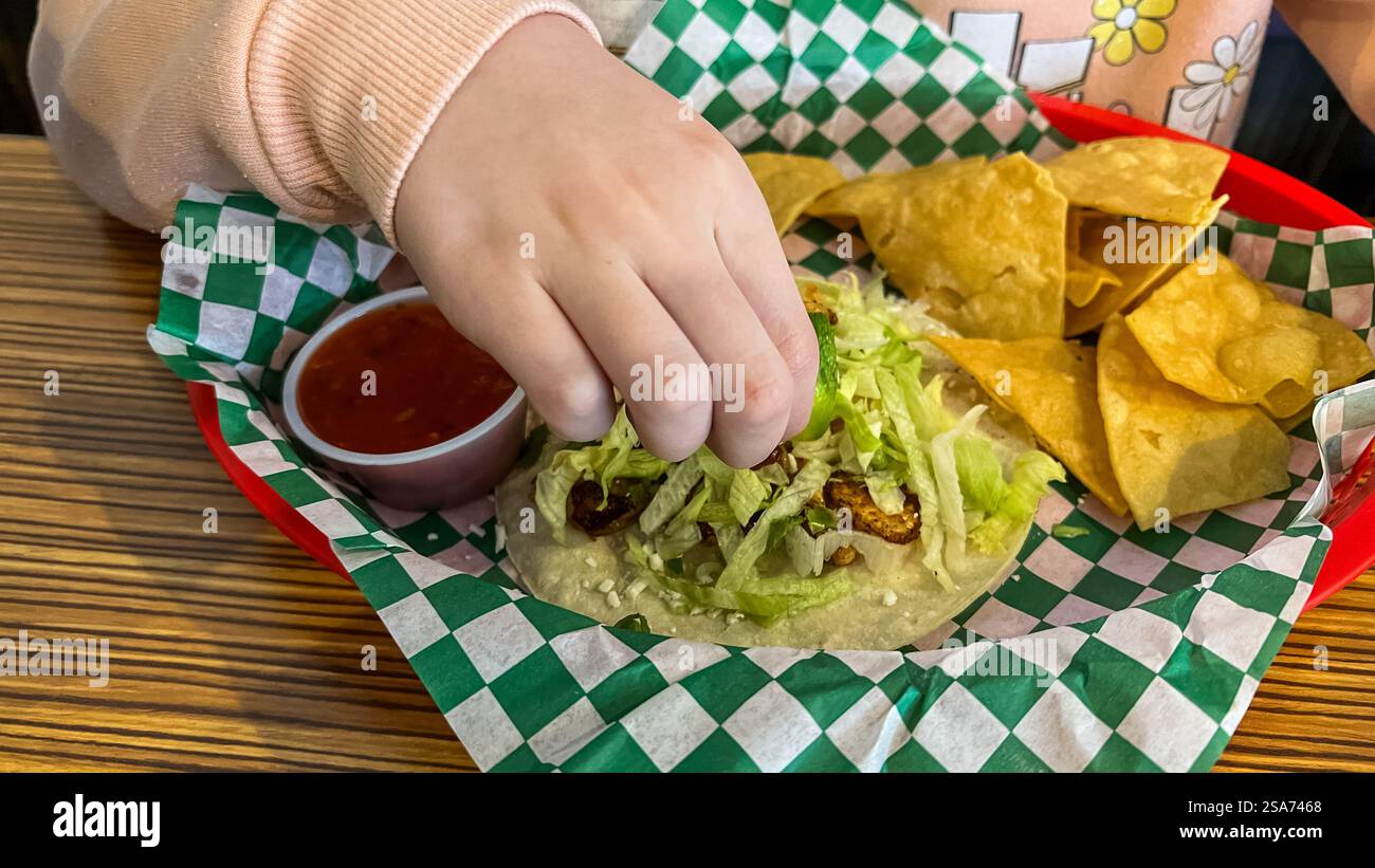 Child Eating Taco with Chips and Salsa Stock Photo - Alamy