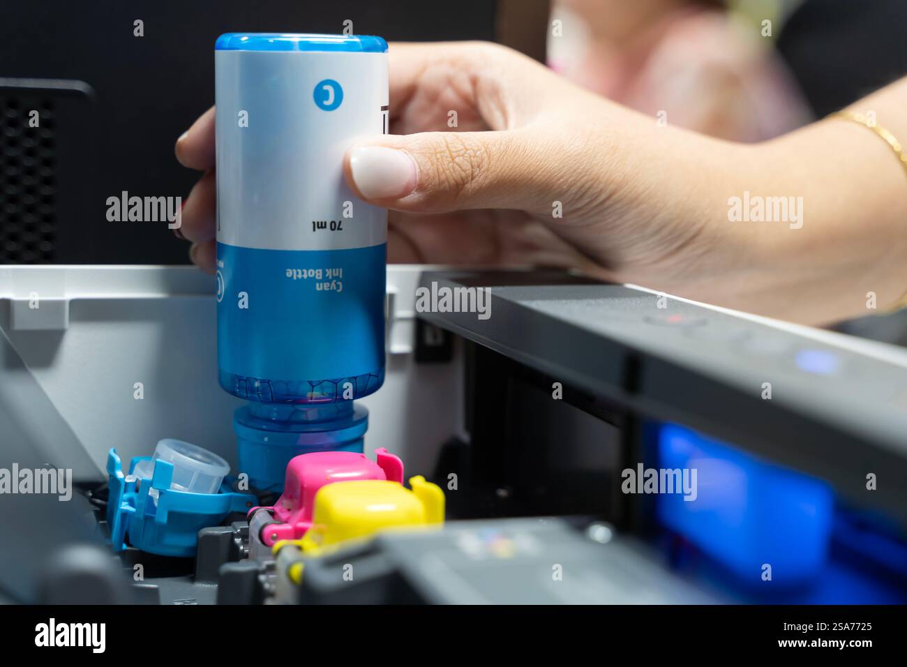 Hand holding ink bottle. Refill ink tank for ink jet Printer. Employees ...