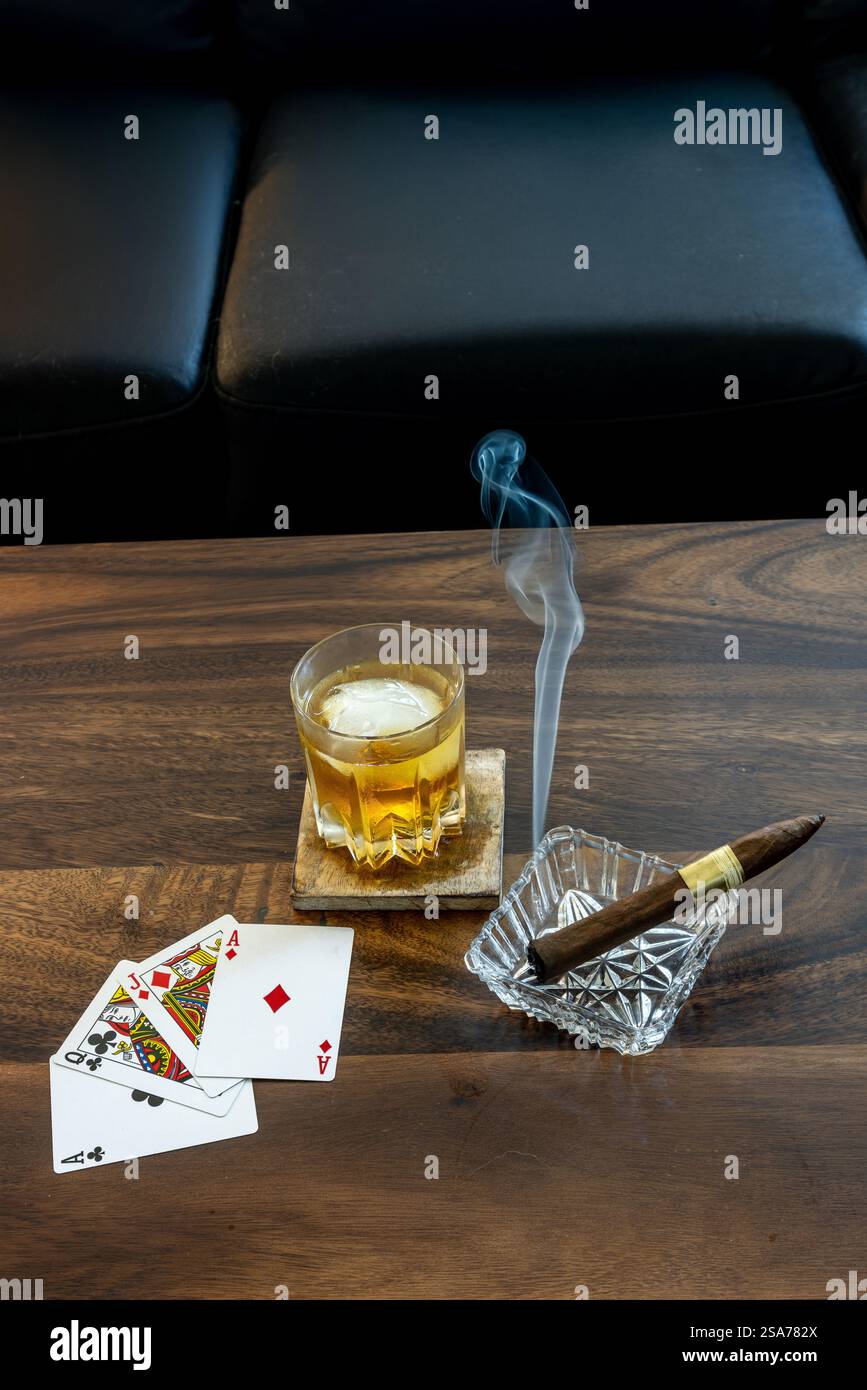 Playing cards in front of a crystal glass of whisky with an ice cube ...