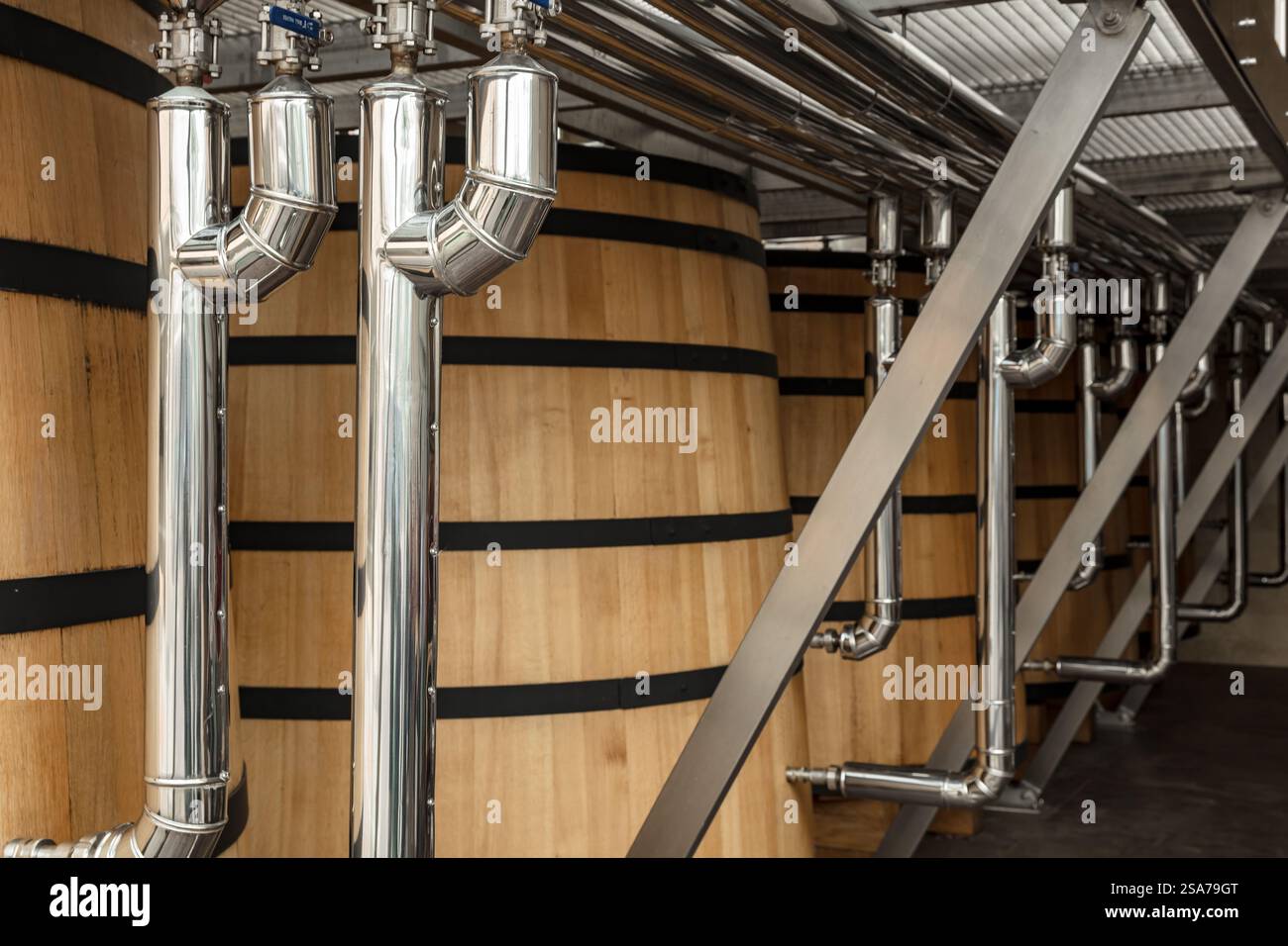 A series of pipes are attached to wooden barrels. The barrels are lined ...