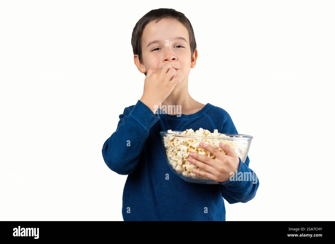 Dark haired boy eating popcorn over isolated white background with a ...
