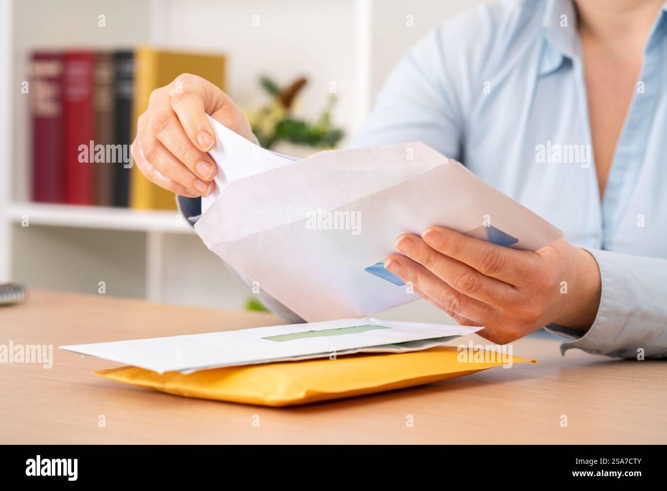 Close up of woman hands putting a letter inside an envelope on a desk ...