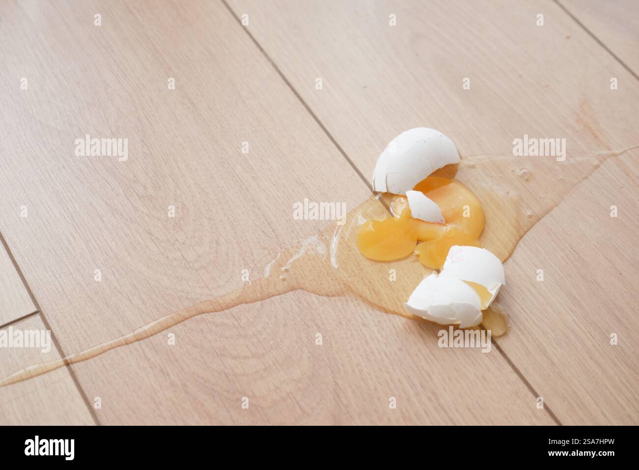 Egg yolk spills onto wooden floor in kitchen accident Stock Photo - Alamy
