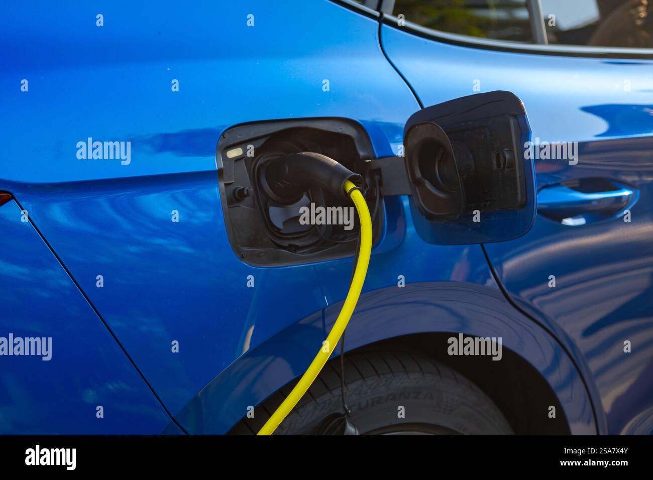 Charging an electric vehicle with a yellow cable at a public charging ...