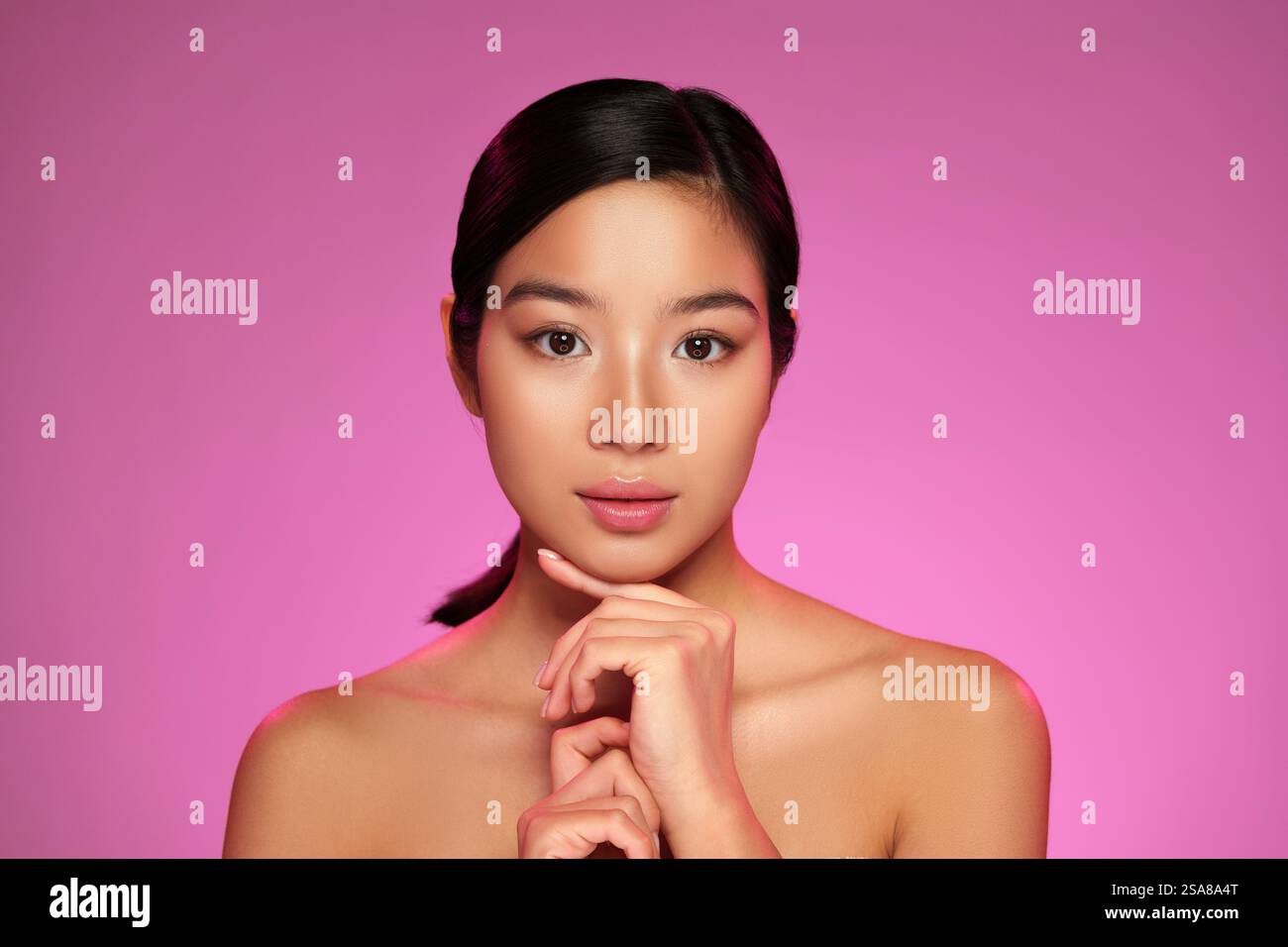 Model poses gracefully with a soft expression against a vibrant pink ...