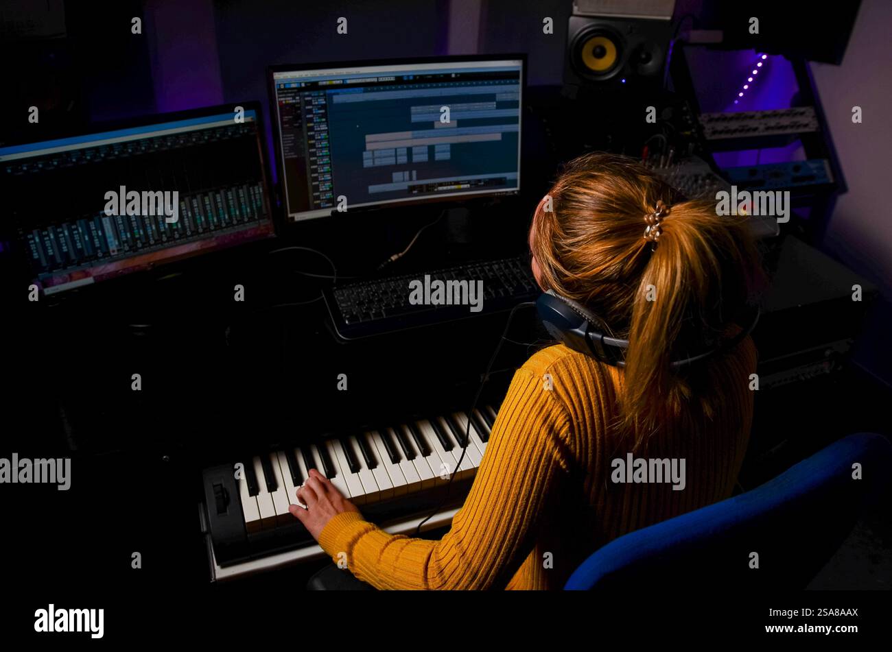 Female music producer composing music using computer, keyboard and ...