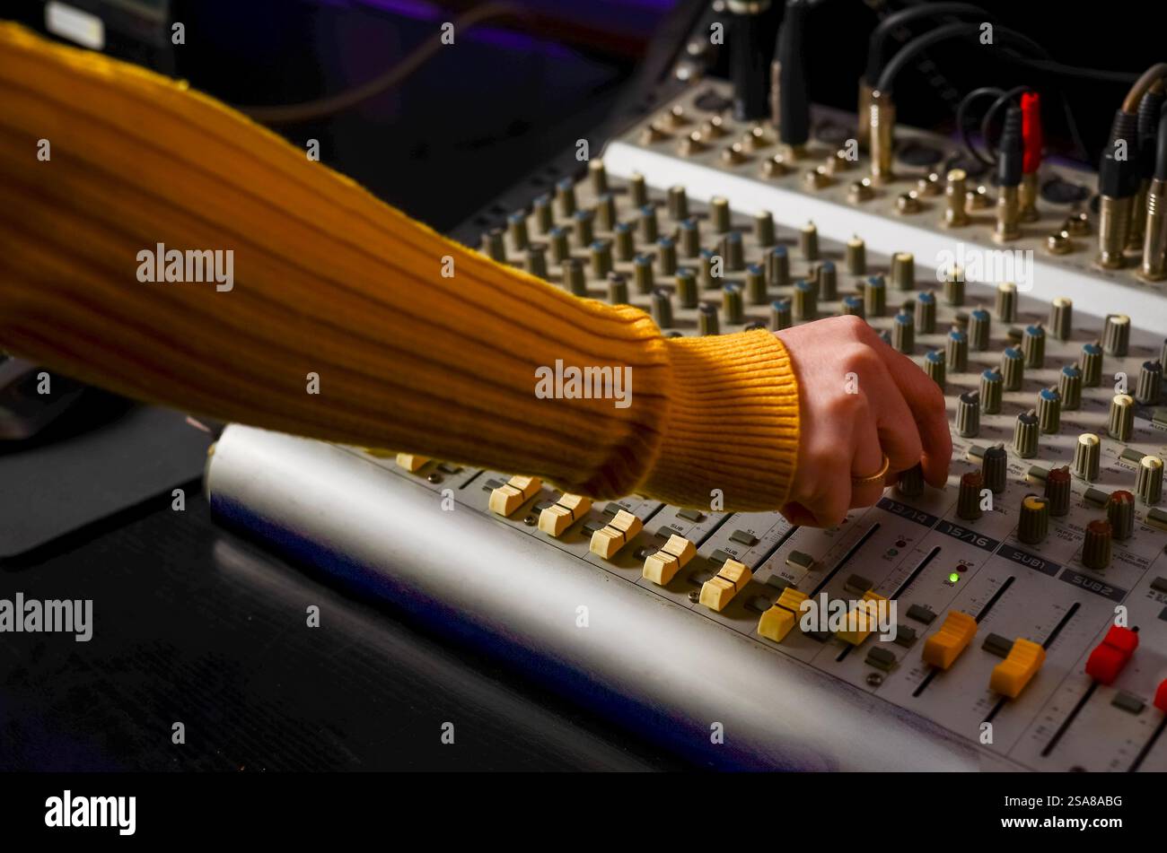Sound engineer adjusting audio levels on a mixing console in a ...