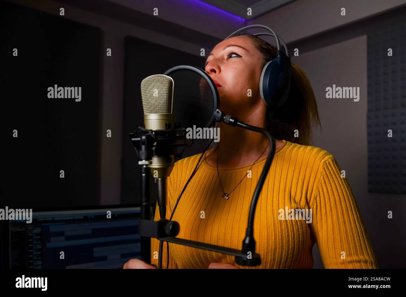 Female singer wearing headphones recording a song using a professional ...