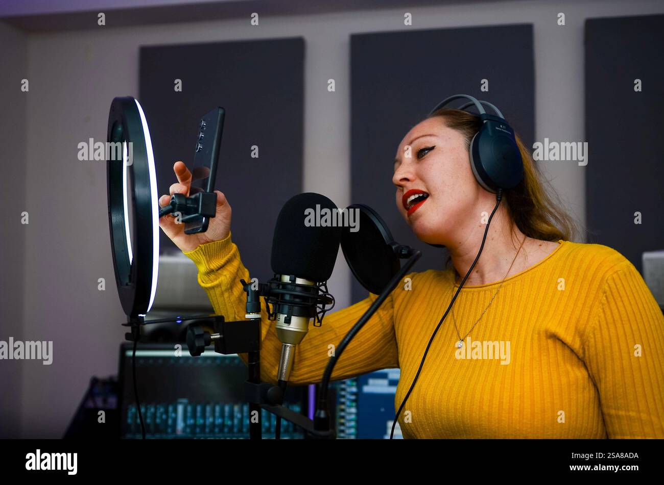 Female singer wearing headphones using a professional microphone and a ...