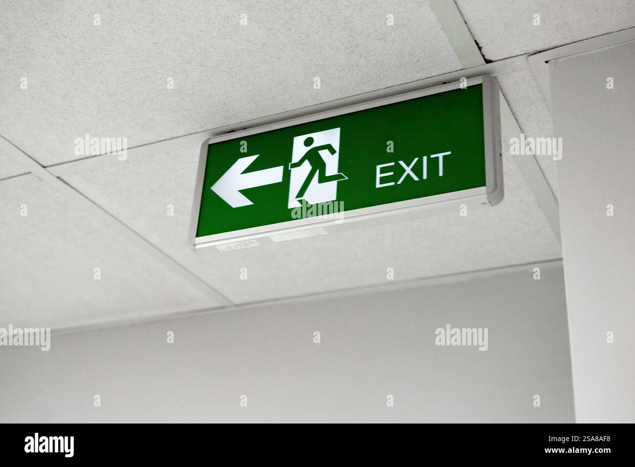 Clear exit sign directing individuals to the left in a well-lit indoor ...