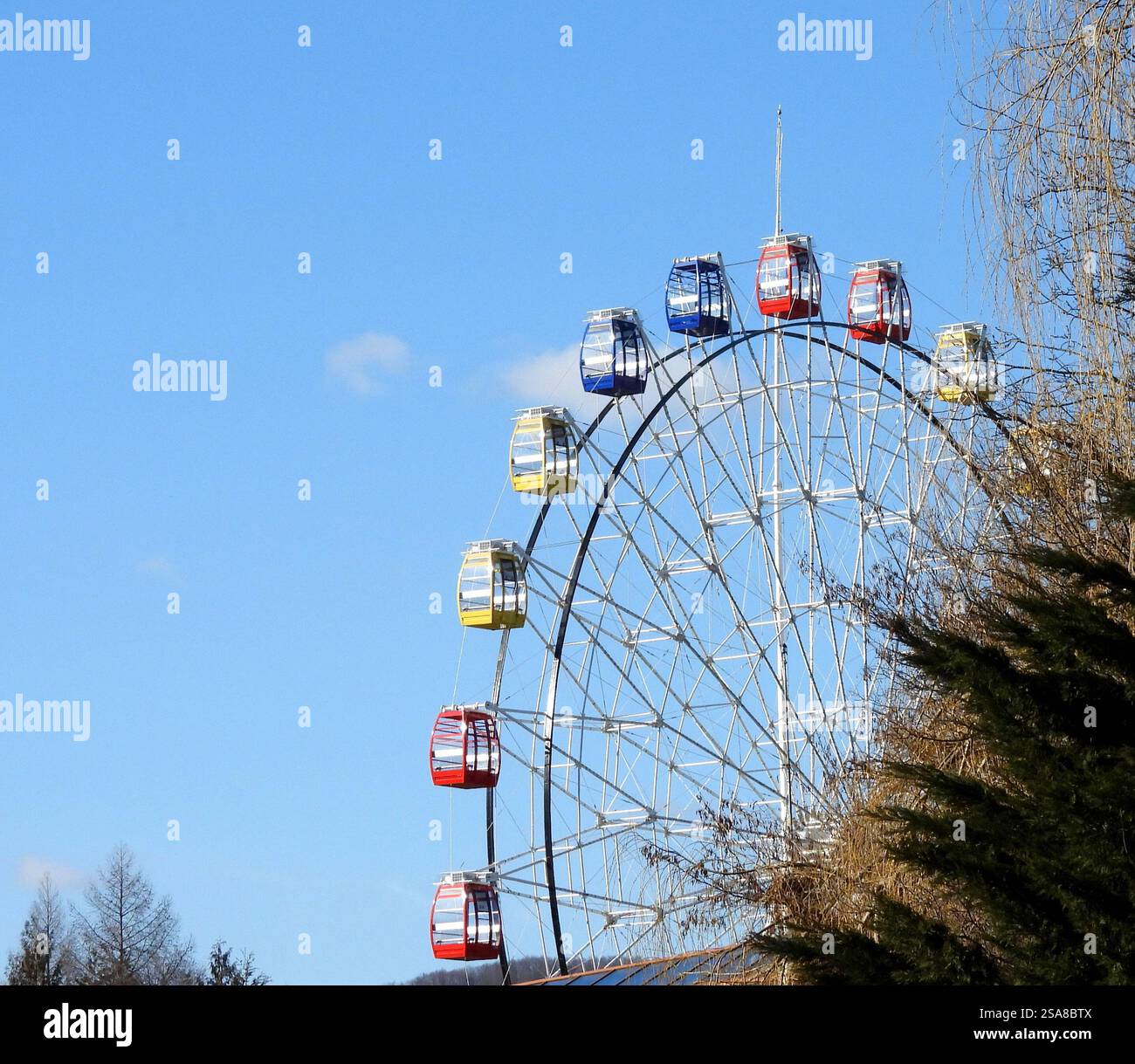Ferris wheel in the park with red, blue and yellow cars Stock Photo - Alamy