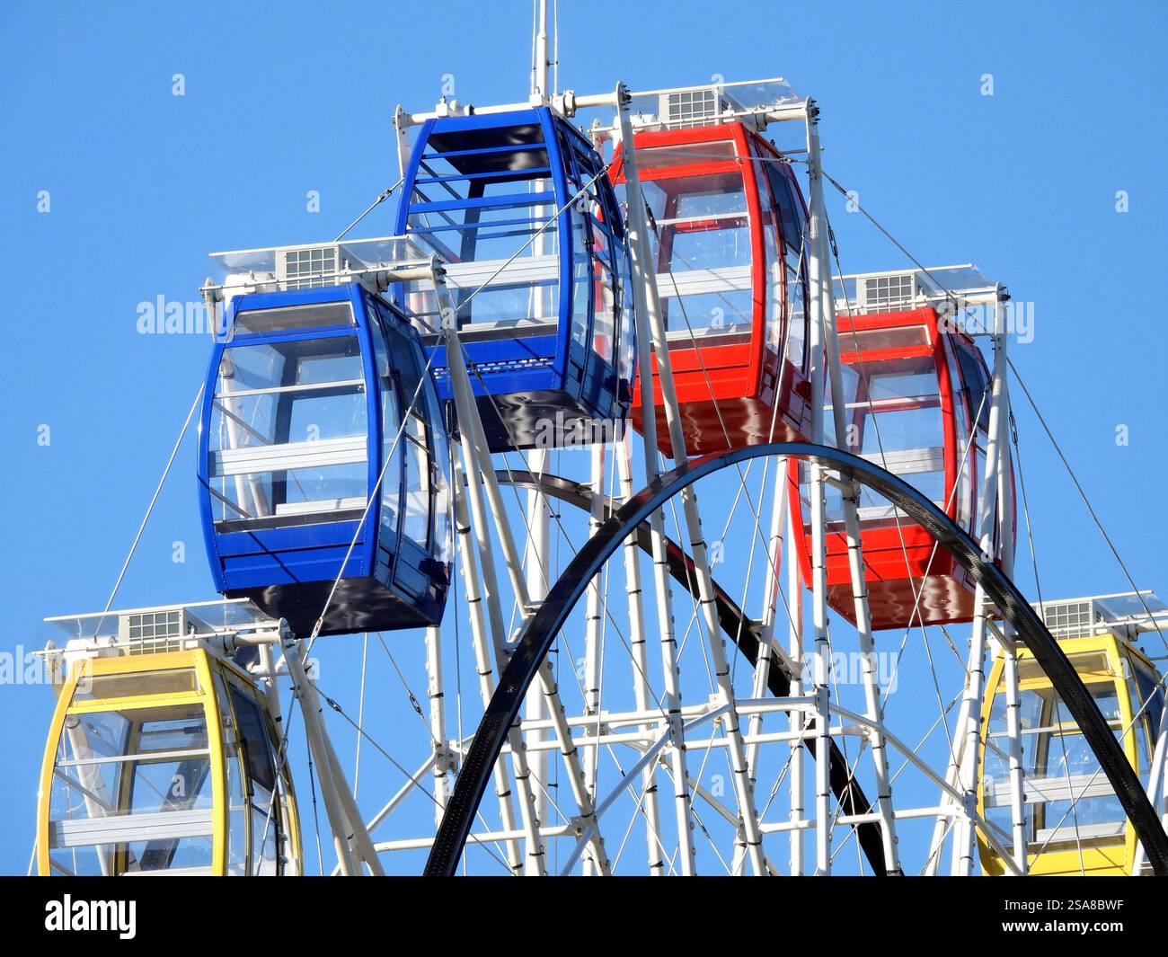 Ferris wheel in the park with red, blue and yellow cars Stock Photo - Alamy