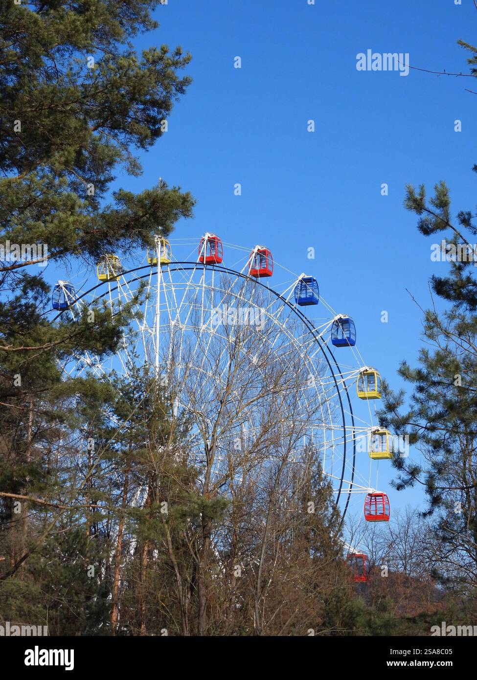 Ferris wheel in the park with red, blue and yellow cars Stock Photo - Alamy