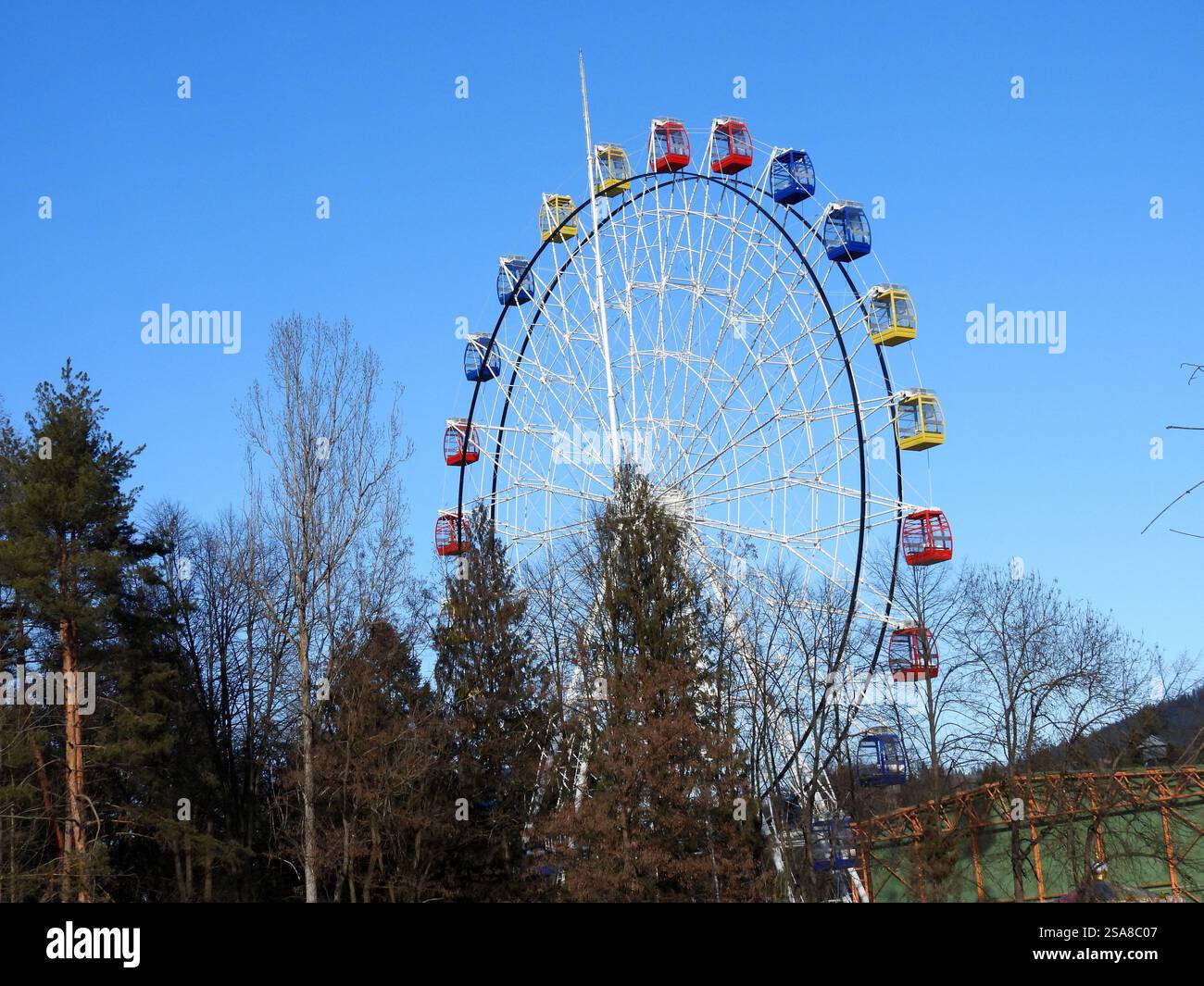 Ferris wheel in the park with red, blue and yellow cars Stock Photo - Alamy
