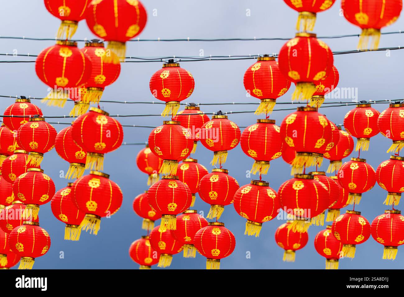 Red Chinese lanterns hanging in rows against a cloudy sky background Stock Photo - Alamy