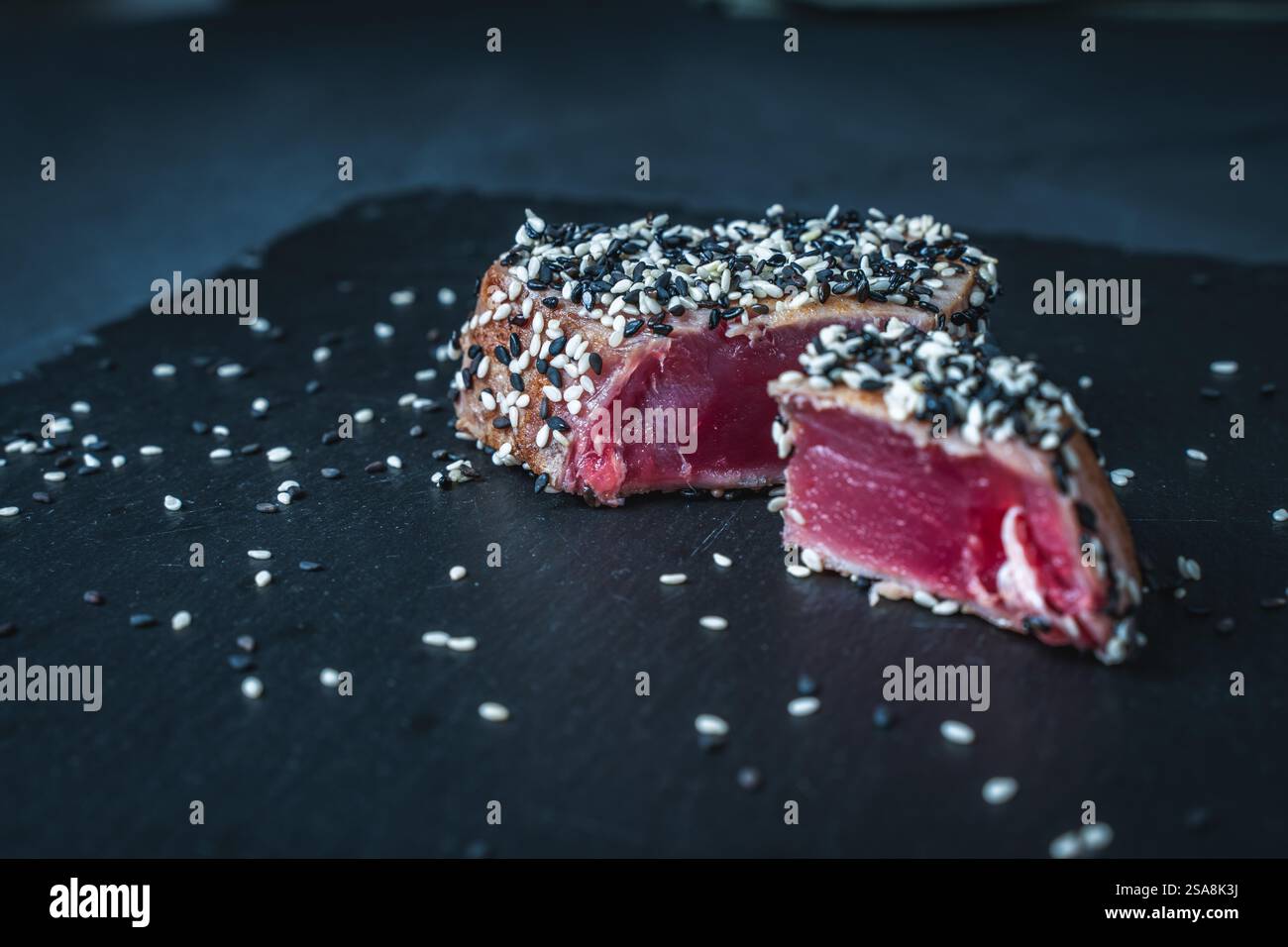 Tuna fried with black and white sesame seeds on a dark mica board on a ...