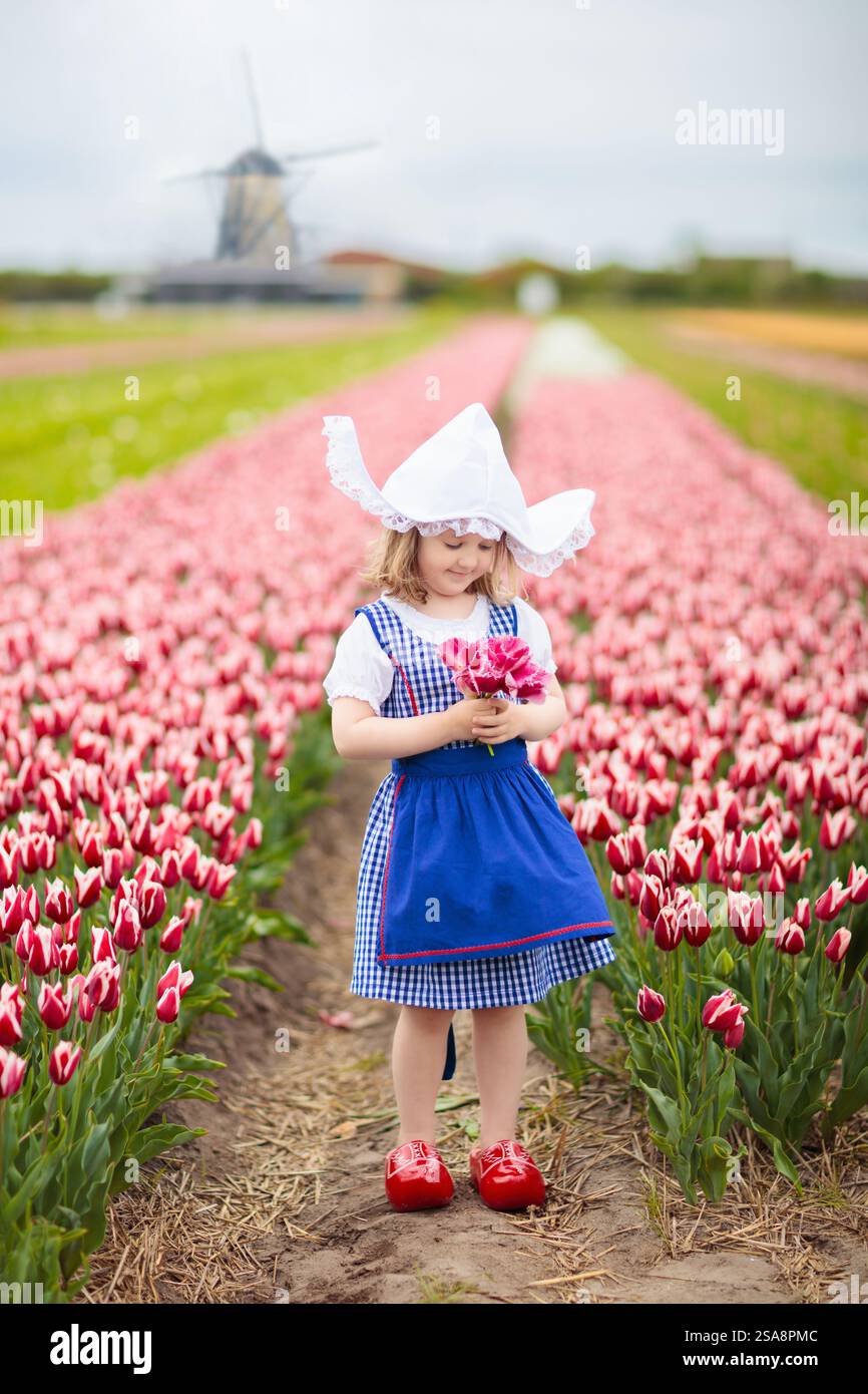Happy Dutch children playing in blooming tulip flowers field. Boy and ...