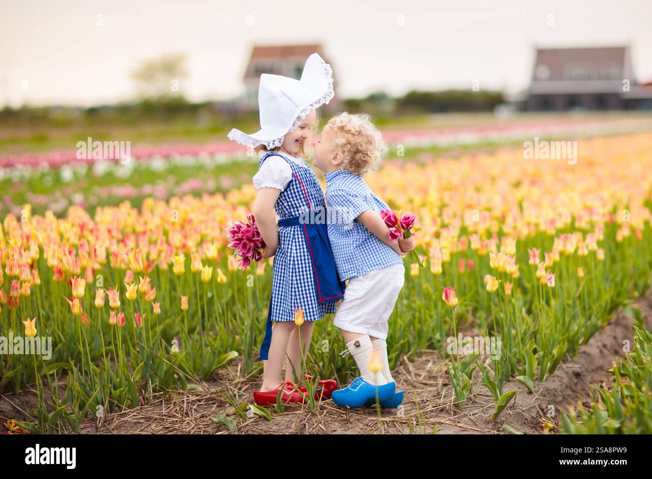 Happy Dutch children playing in blooming tulip flowers field. Boy and ...