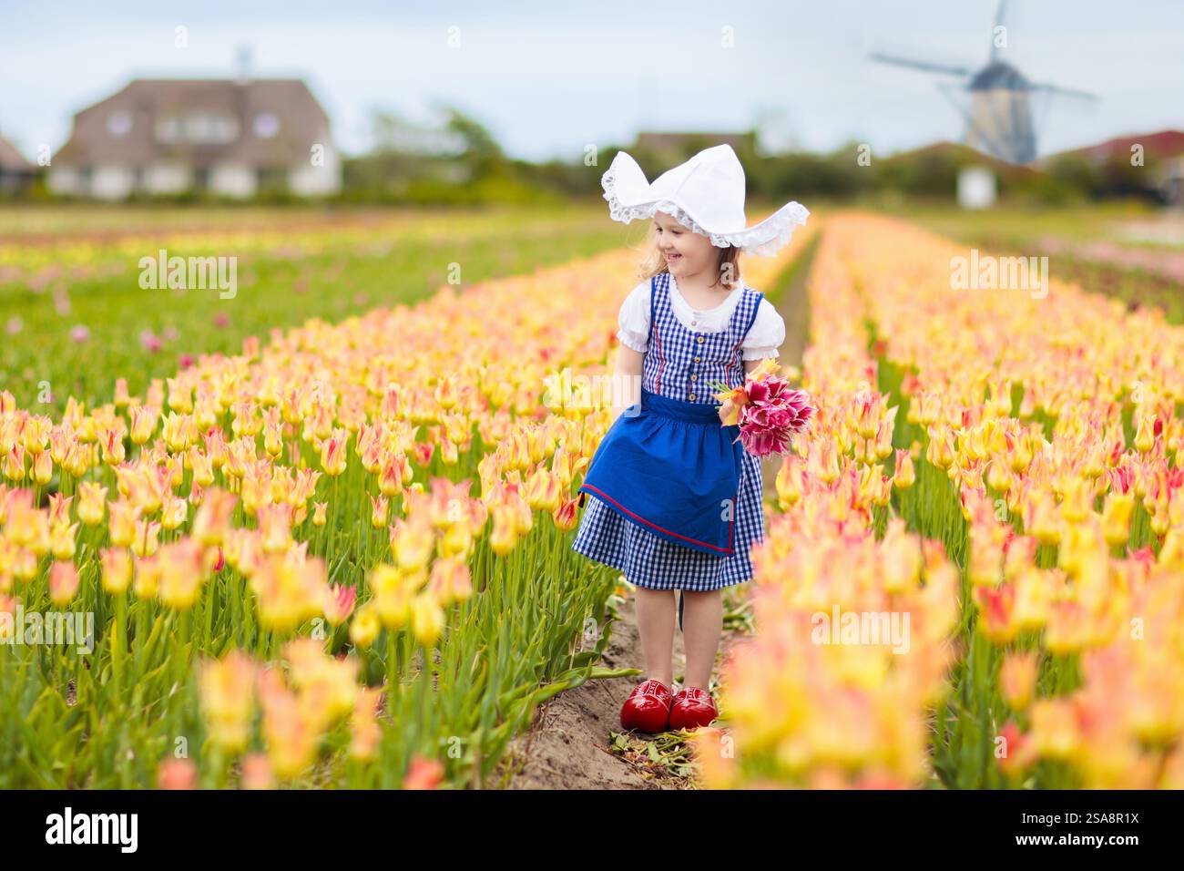 Happy Dutch children playing in blooming tulip flowers field. Boy and ...