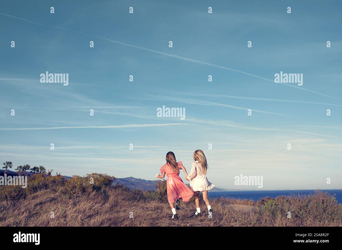 2 girls running on cliff by the ocean Stock Photo - Alamy