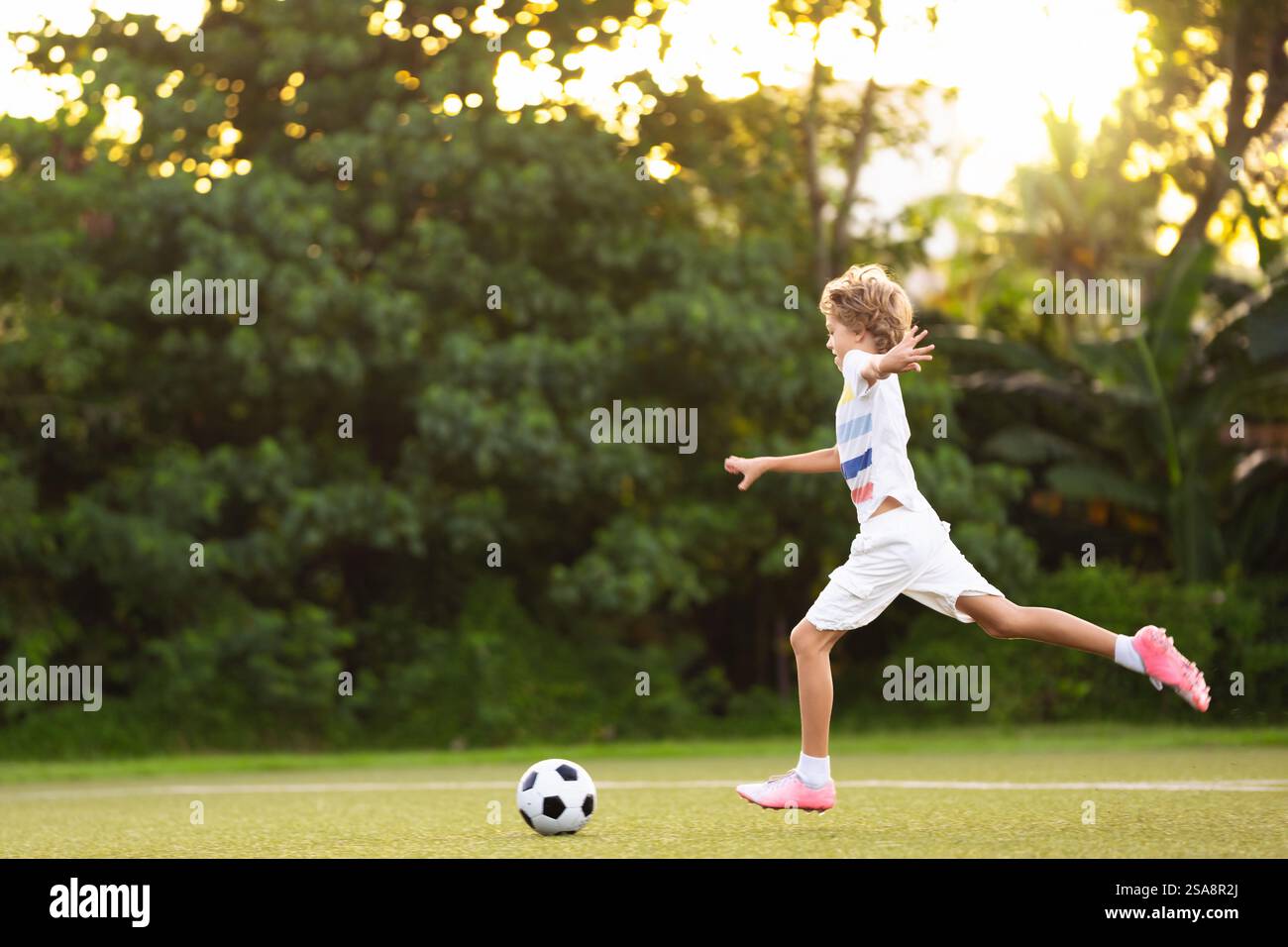 Child playing football. Kids play soccer on outdoor pitch. Little boy ...