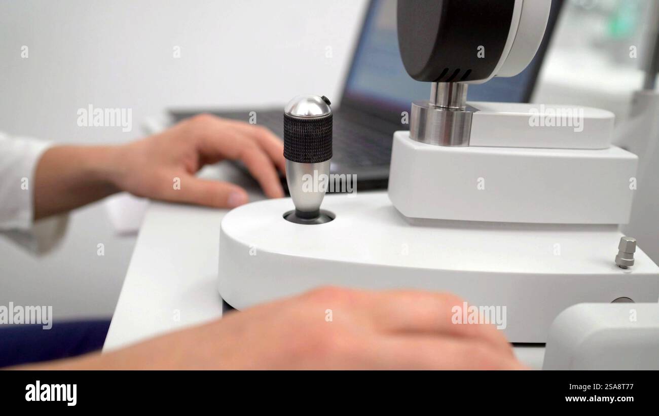 Doctor adjusting medical equipment with a joystick and checking data on ...