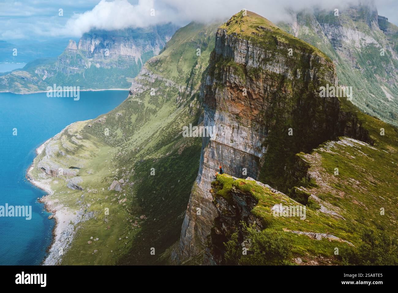 Man traveler sitting on cliff mountain traveling solo in Norway aerial ...