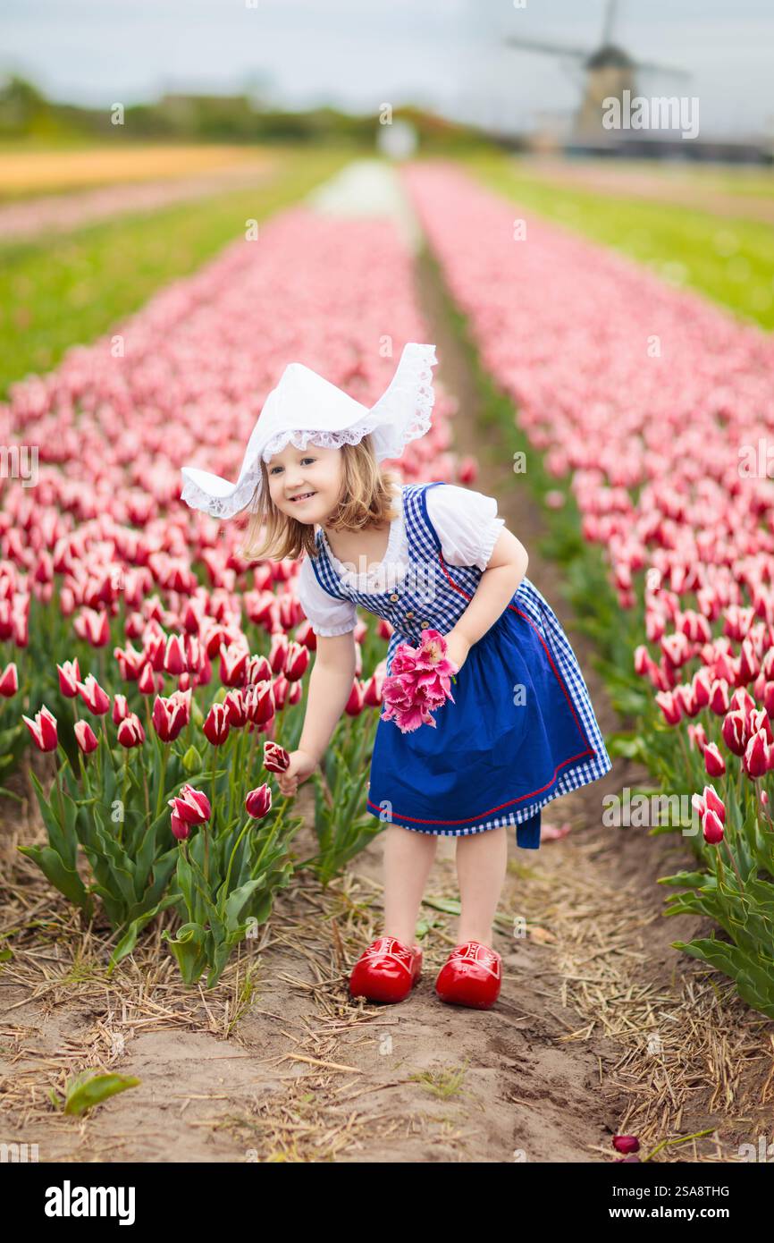 Happy Dutch children playing in blooming tulip flowers field. Boy and ...