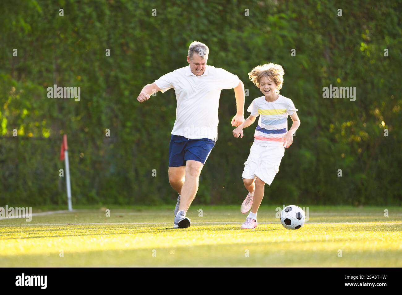 Child playing football. Kids play soccer on outdoor pitch. Little boy ...