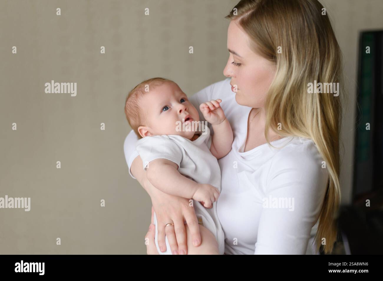 A loving mother holds,rocking, sings a song to her baby. A mother looks ...
