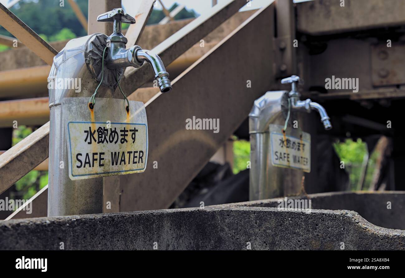 Two public water faucets next to a metal staircase and platform, on ...