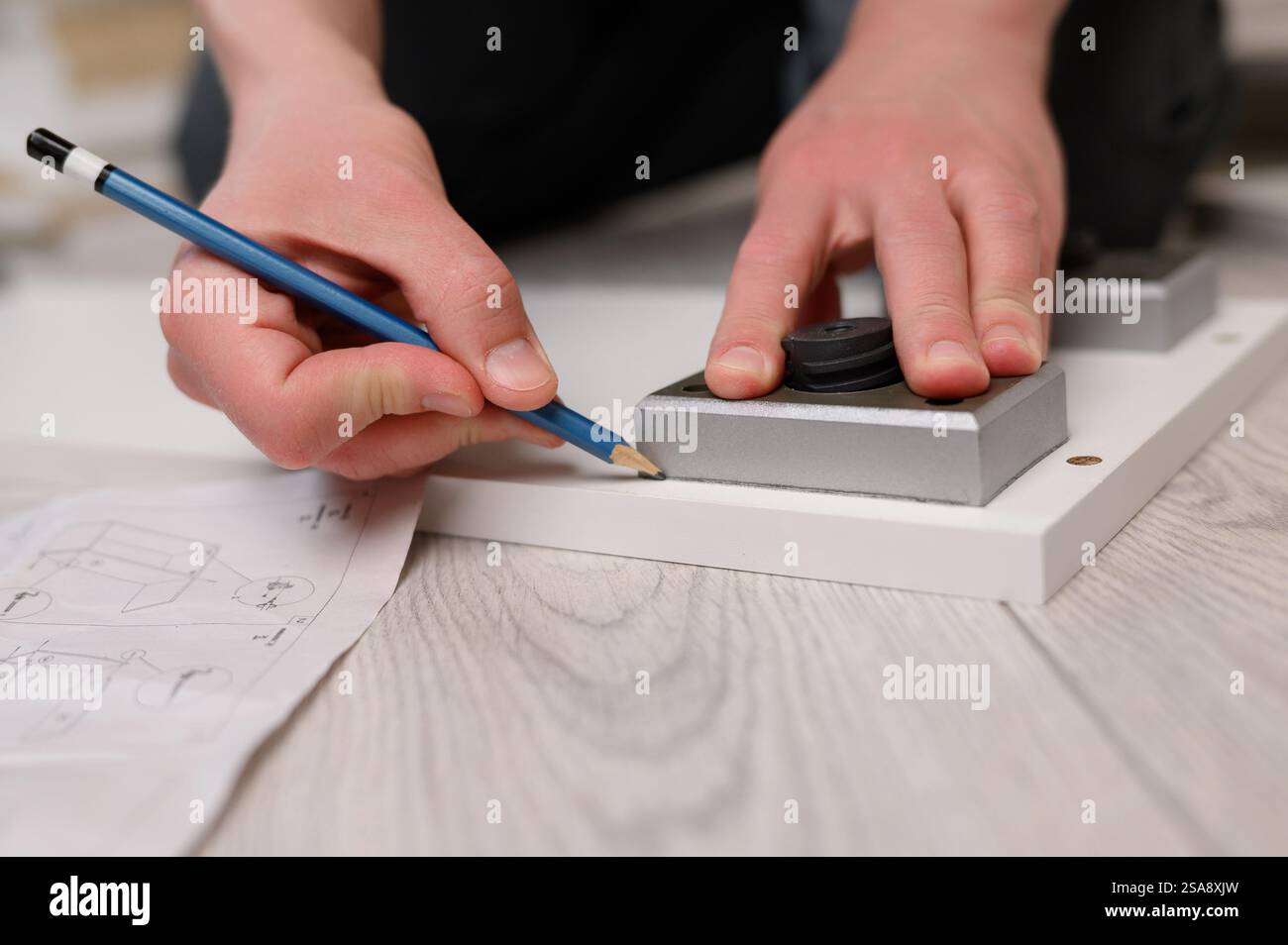 Furniture assembly. The worker makes markings with a pencil for ...