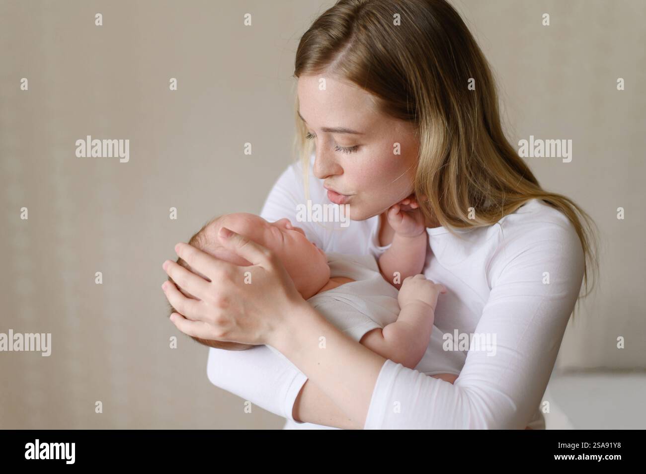 Child cries in his mom arms, a tired mother looks at her newborn baby ...