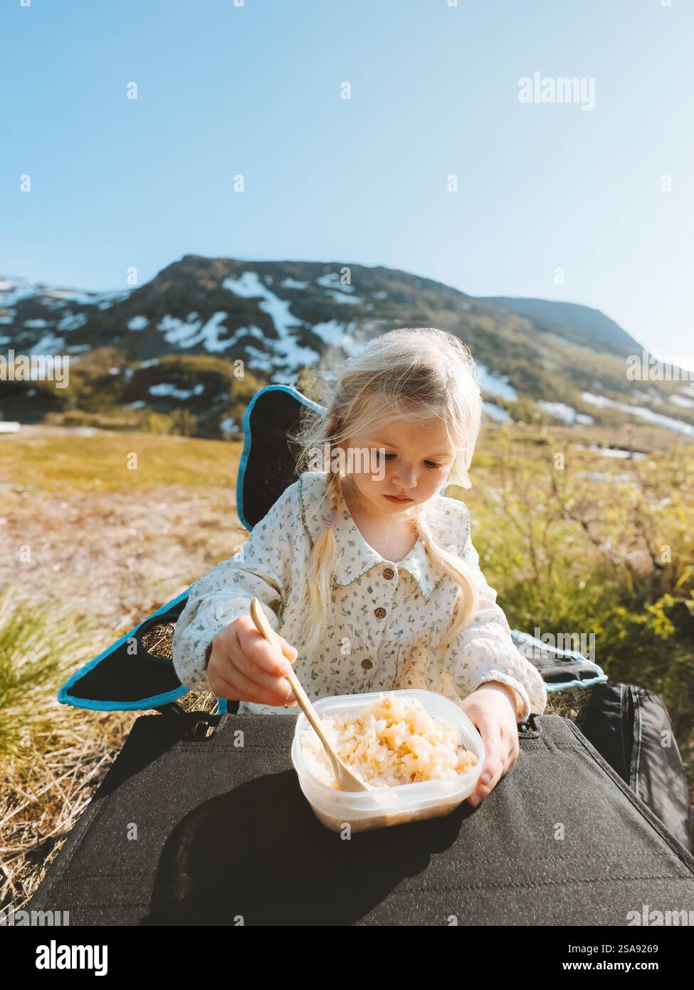 Child girl eating rice in lunch box breakfast picnic in mountains ...
