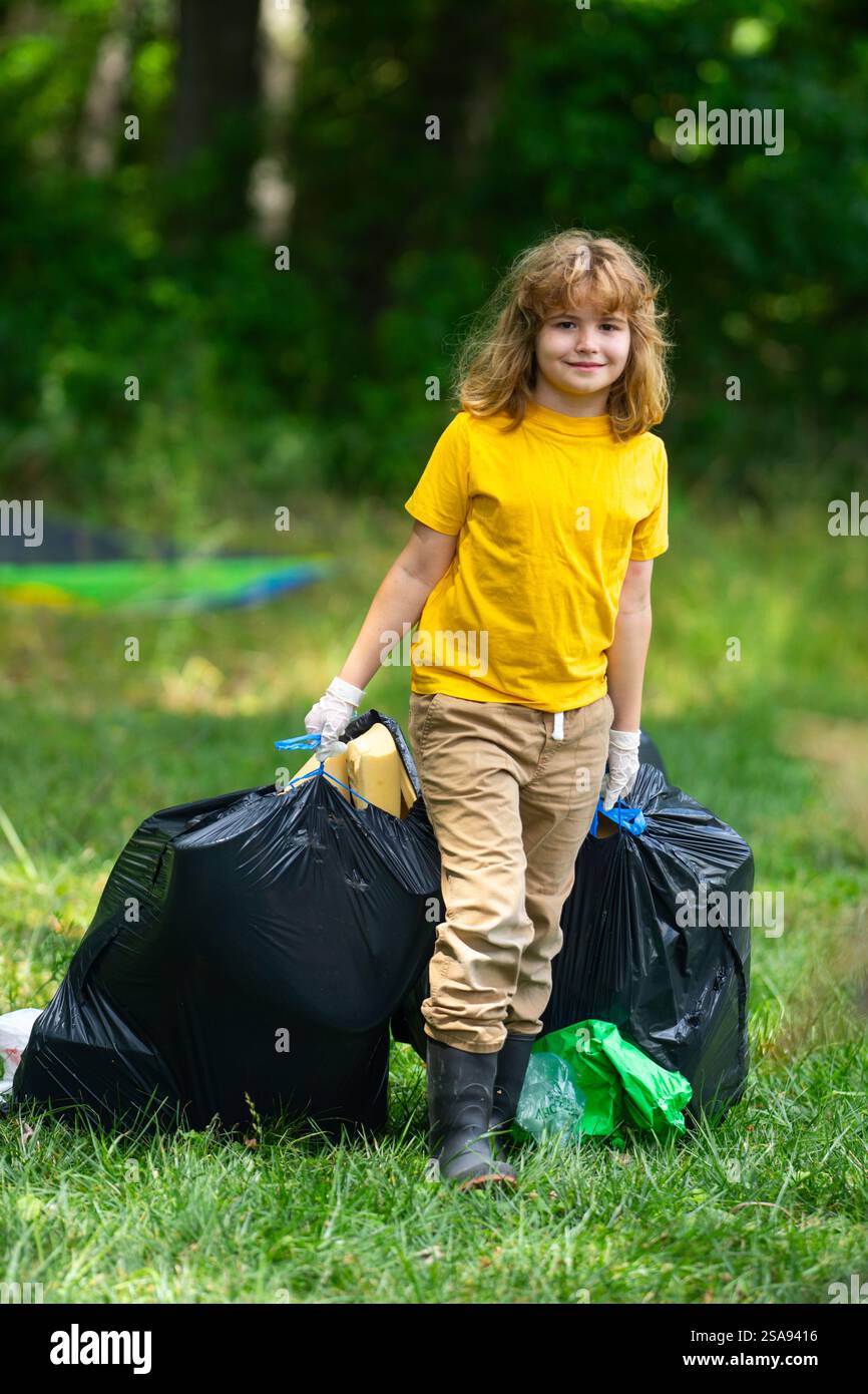 Environment plastic pollution. Volunteer kid collecting trash in the forest and holding a ...
