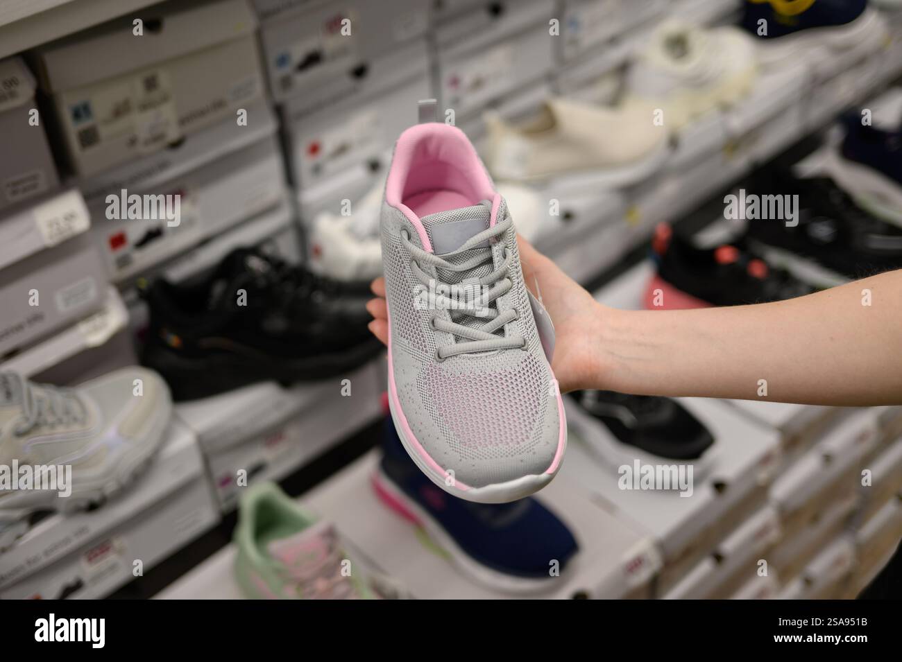 A woman chooses shoes in a shopping center in the sporting goods ...