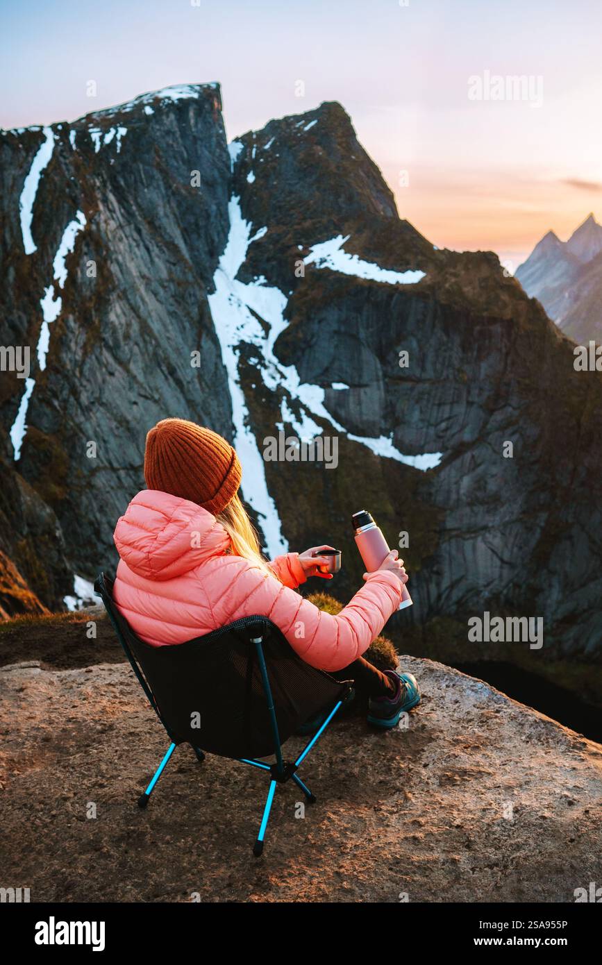 Woman adventurer relaxing in camping chair with thermos in mountains ...