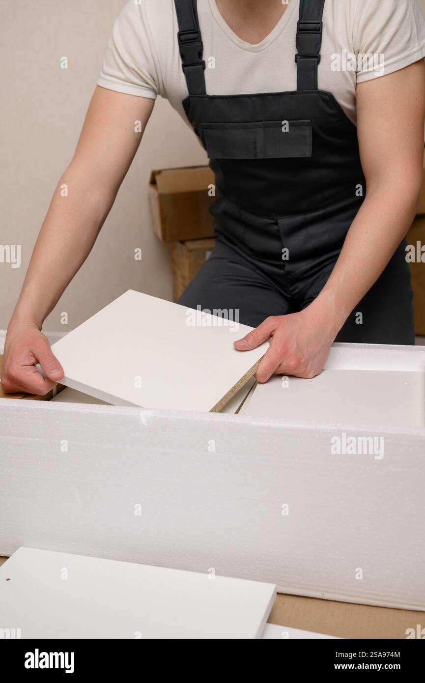 Man unpacking boxes with furniture boards for furniture assembly ...
