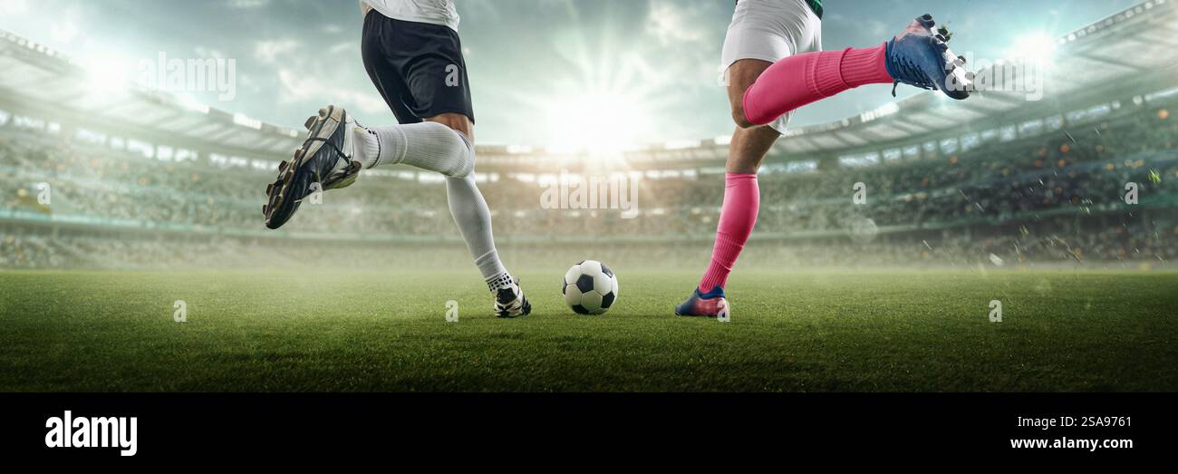 Two soccer players in sport uniforms concurrently kicking soccer ball ...