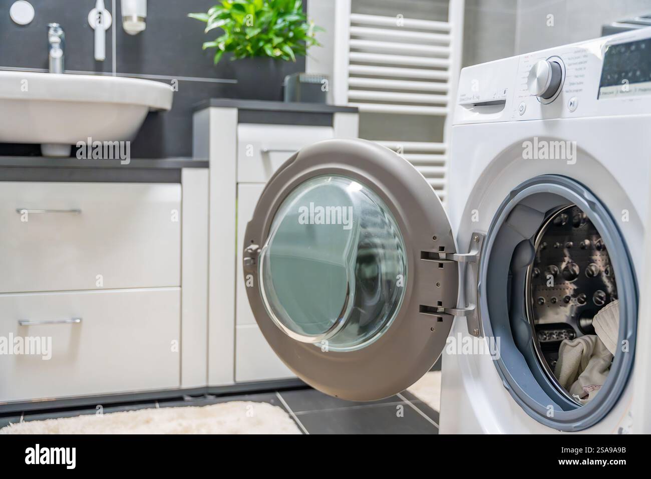 Washing machine with open door in modern, white and grey bathroom in ...
