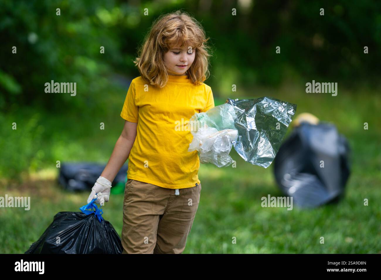 Kid in rubber gloves with trash bag clean up garbage on forest outdoor ...