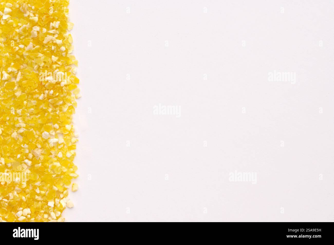 Macro photo of dry yellow corn porridge on a white background. Healthy ...