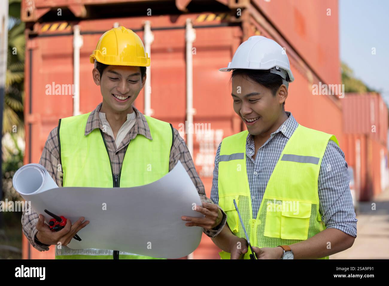 Logistics engineer and colleague reviewing blueprints in a construction setting Stock Photo - Alamy