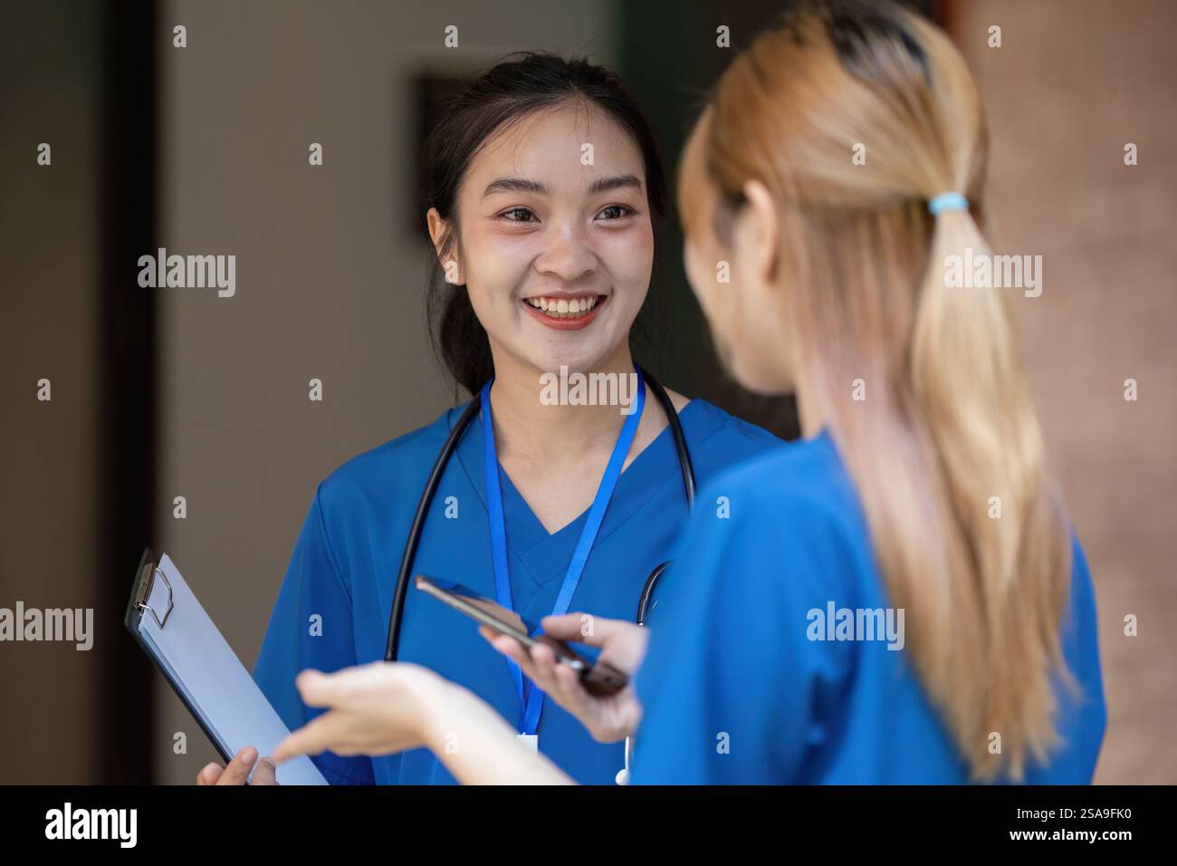 Doctors conversing during a break, sharing smiles and a clipboard Stock Photo - Alamy